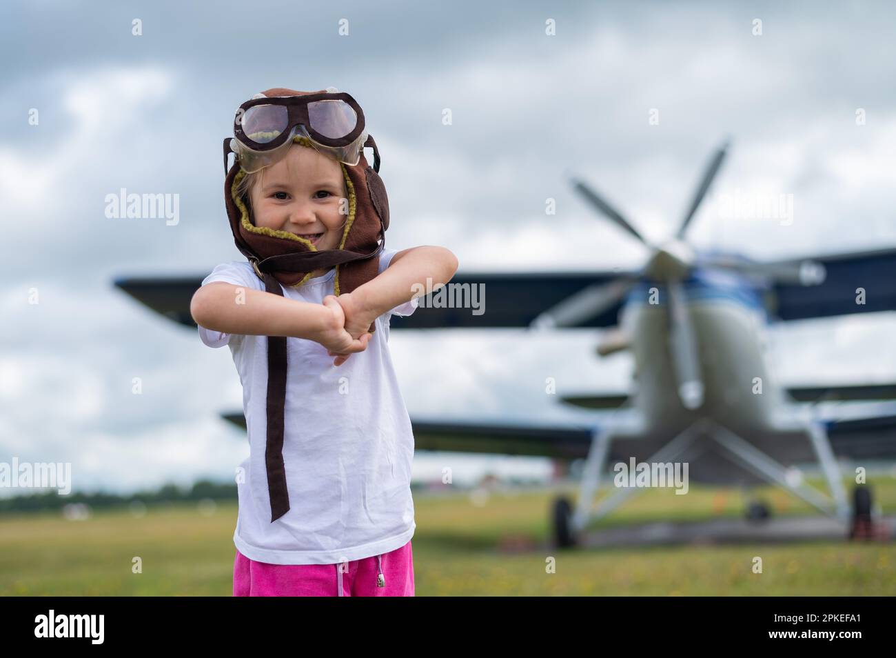 A cute little girl dressed in a cap and glasses of a pilot on the ...