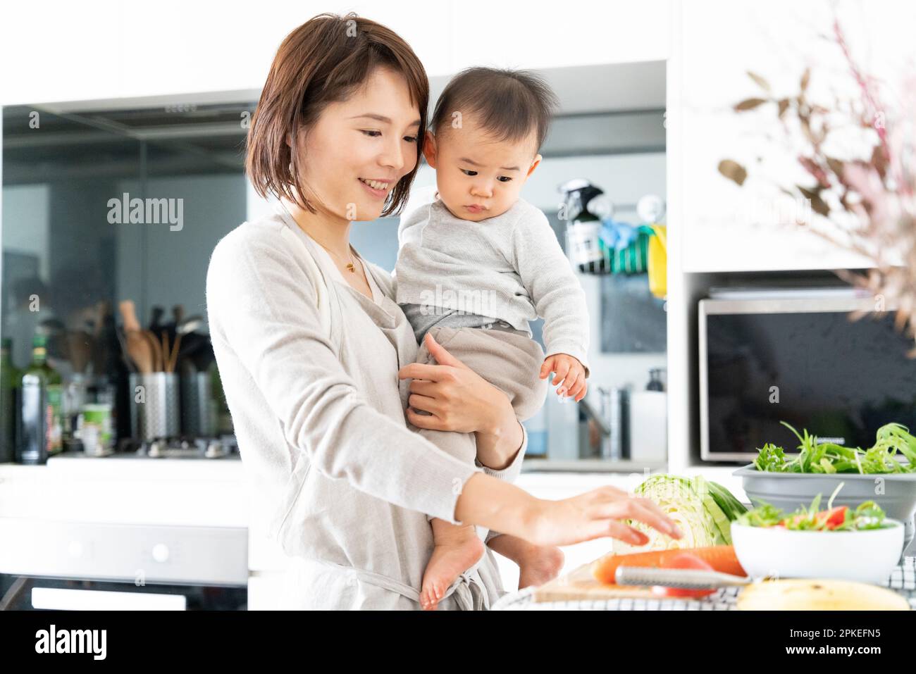 Woman doing housework while holding baby Stock Photo - Alamy