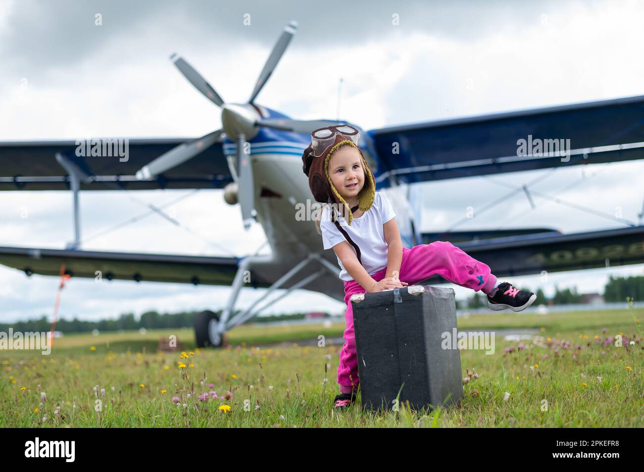 A cute little girl playing on the field by a four-seater private jet ...