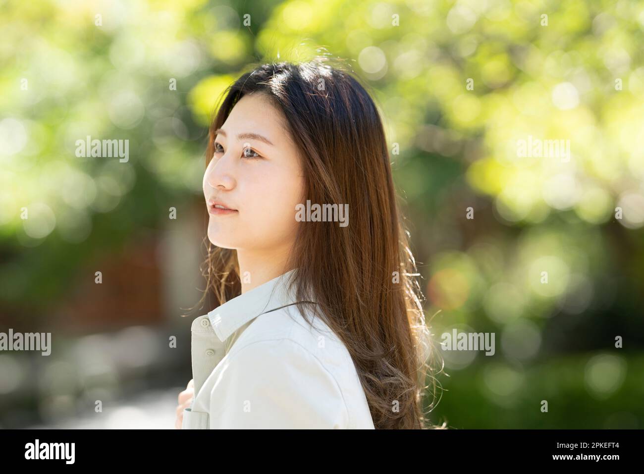 Side view of woman smiling with green in background Stock Photo - Alamy