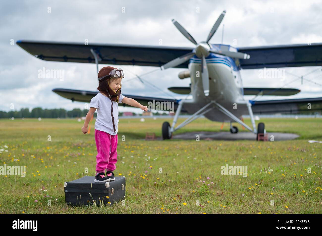 A cute little girl playing on the field by a four-seater private jet ...