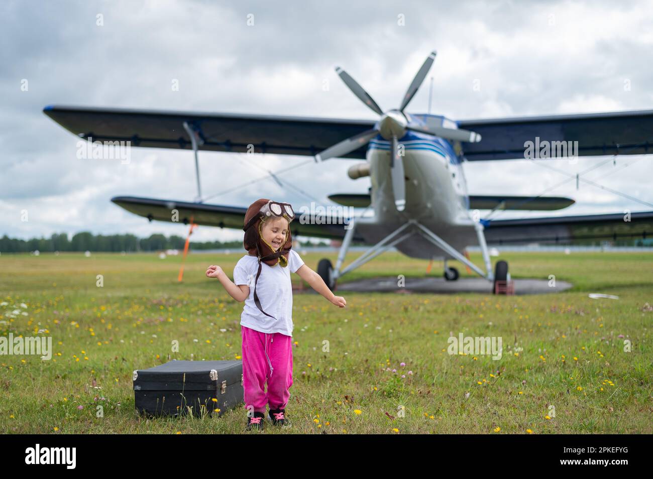 A cute little girl playing on the field by a four-seater private jet ...