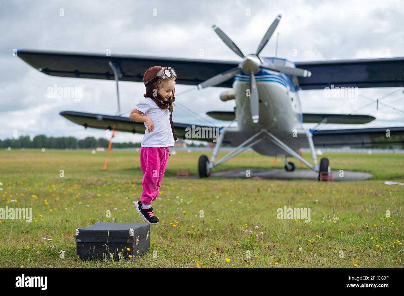 A cute little girl playing on the field by a four-seater private jet ...