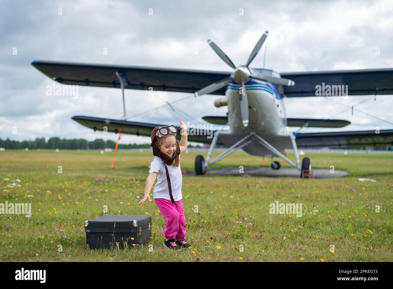 A cute little girl playing on the field by a four-seater private jet ...