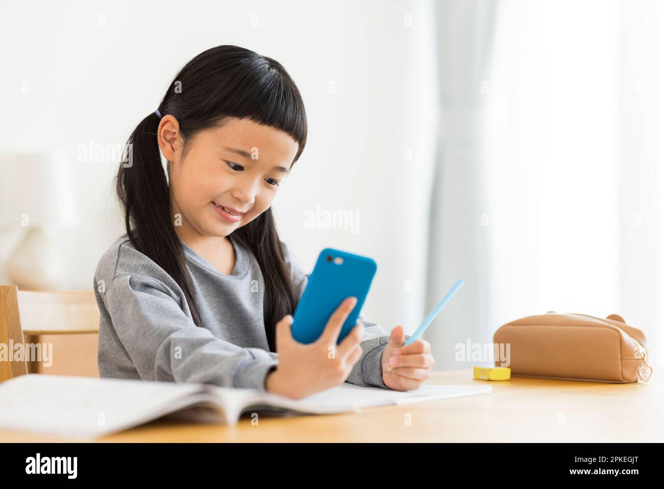 Girl studying while looking at her smartphone Stock Photo - Alamy