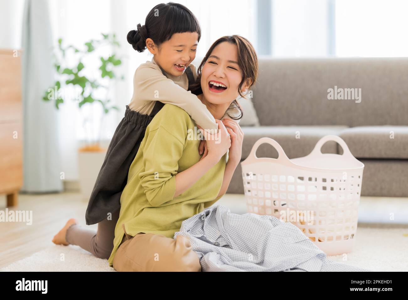 Girl hugging mother folding laundry Stock Photo - Alamy