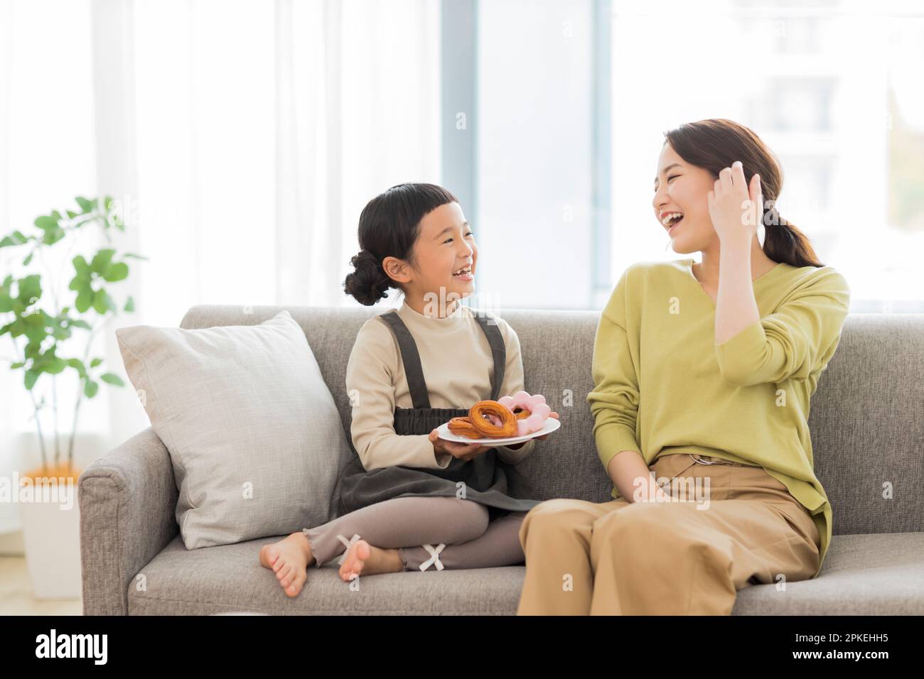 Smiling Girl With Donut And Mother Stock Photo - Alamy