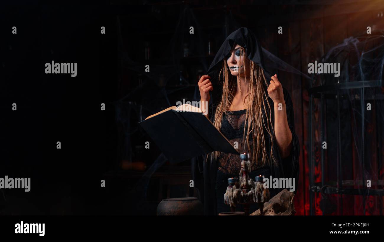 Halloween concept. Witch dressed black hood standing dark dungeon room ...