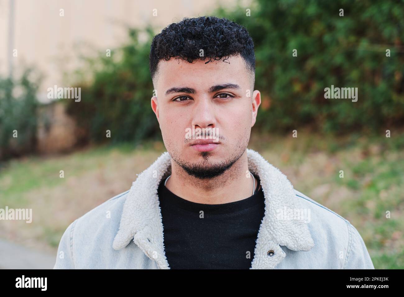 Close up portrait of young guy looking serious at camera standing ...