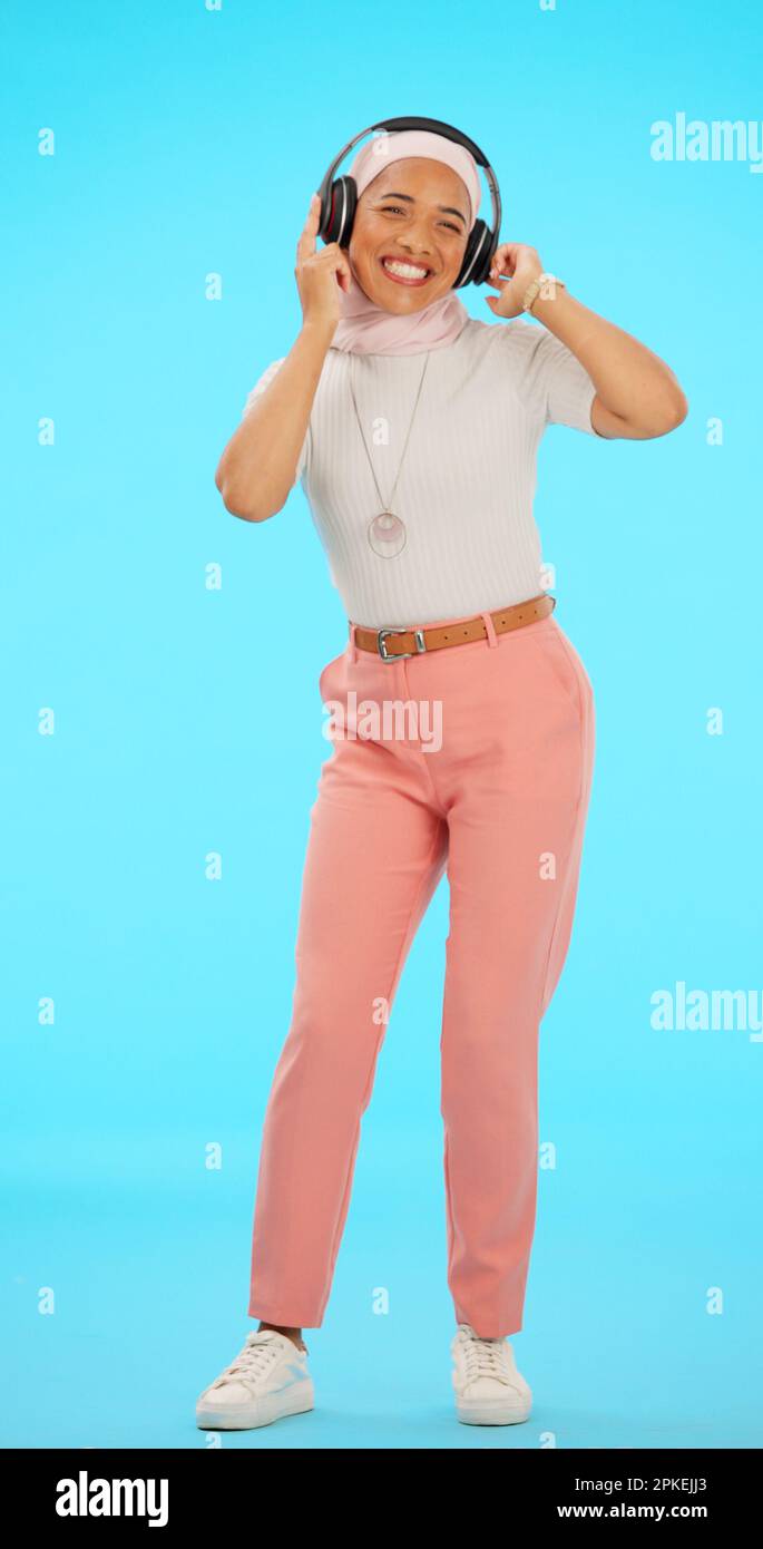 Headphones, dance and Muslim woman in studio on blue background ...