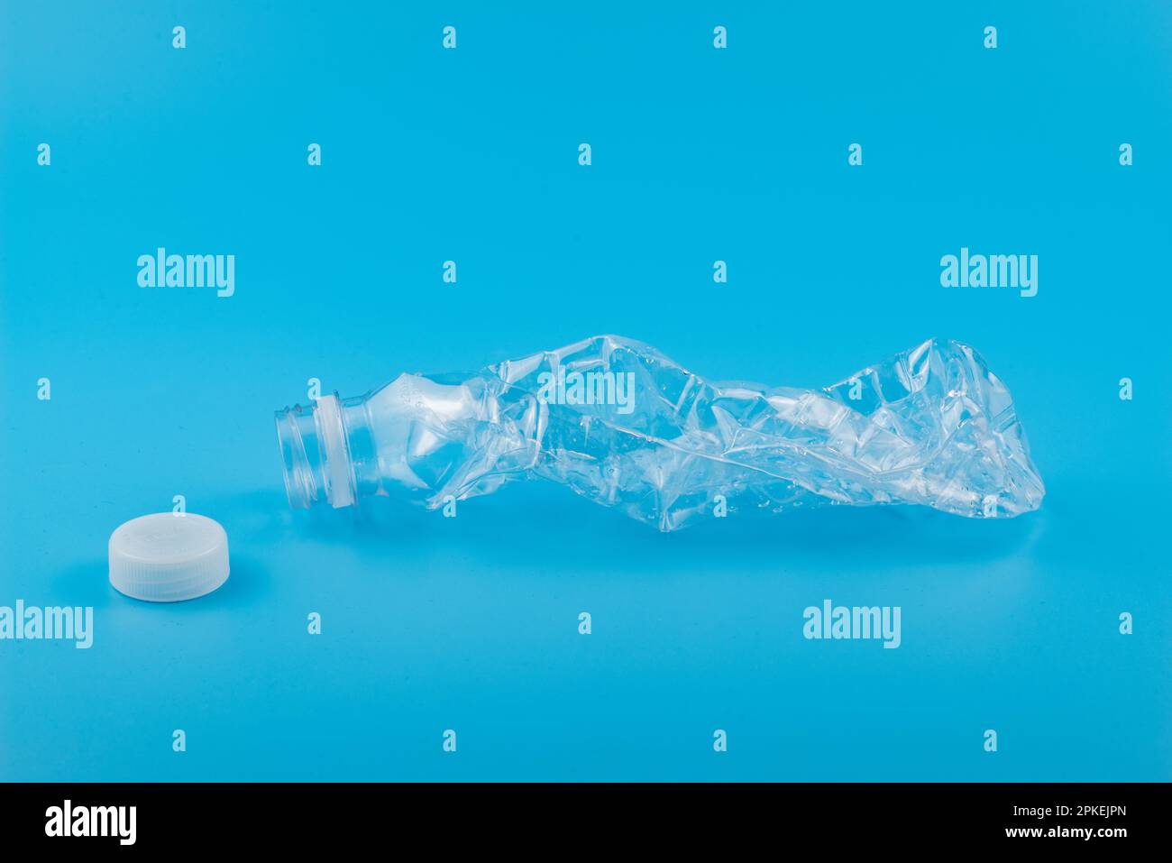 Empty crushed plastic bottle on blue background. Recyclable waste Stock ...