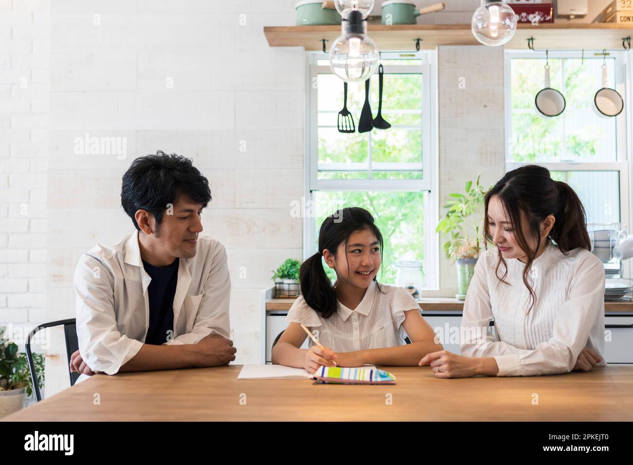 Parents watching over an elementary school girl studying Stock Photo ...