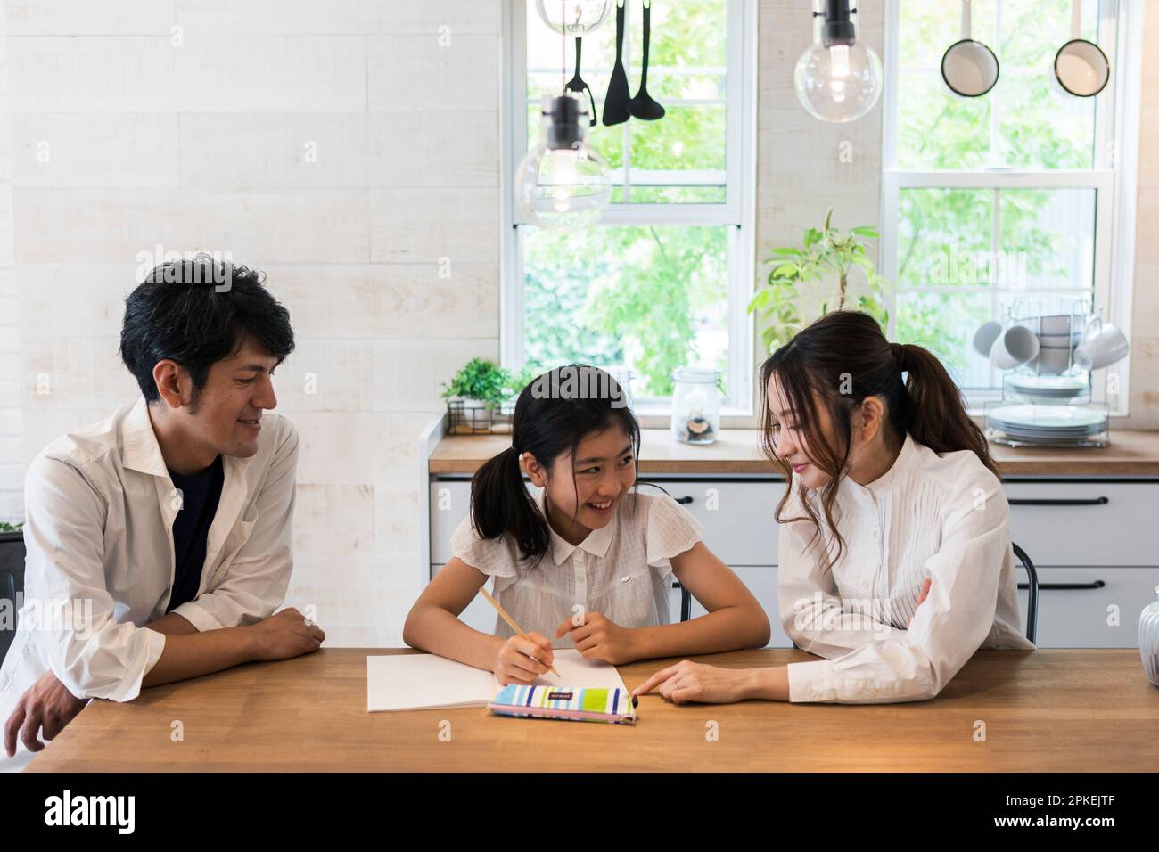 Parents watching over an elementary school girl studying Stock Photo ...