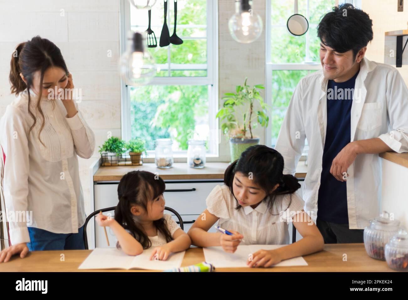Sisters studying and their parents watching over them Stock Photo - Alamy