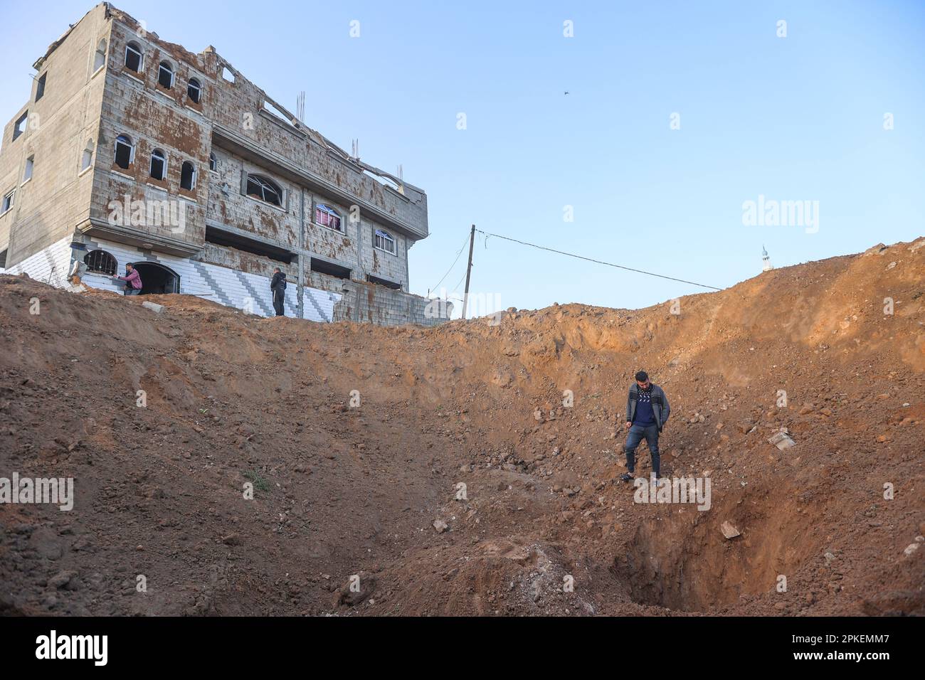 Palestinians walk in front of a destroyed area after Israel launched ...