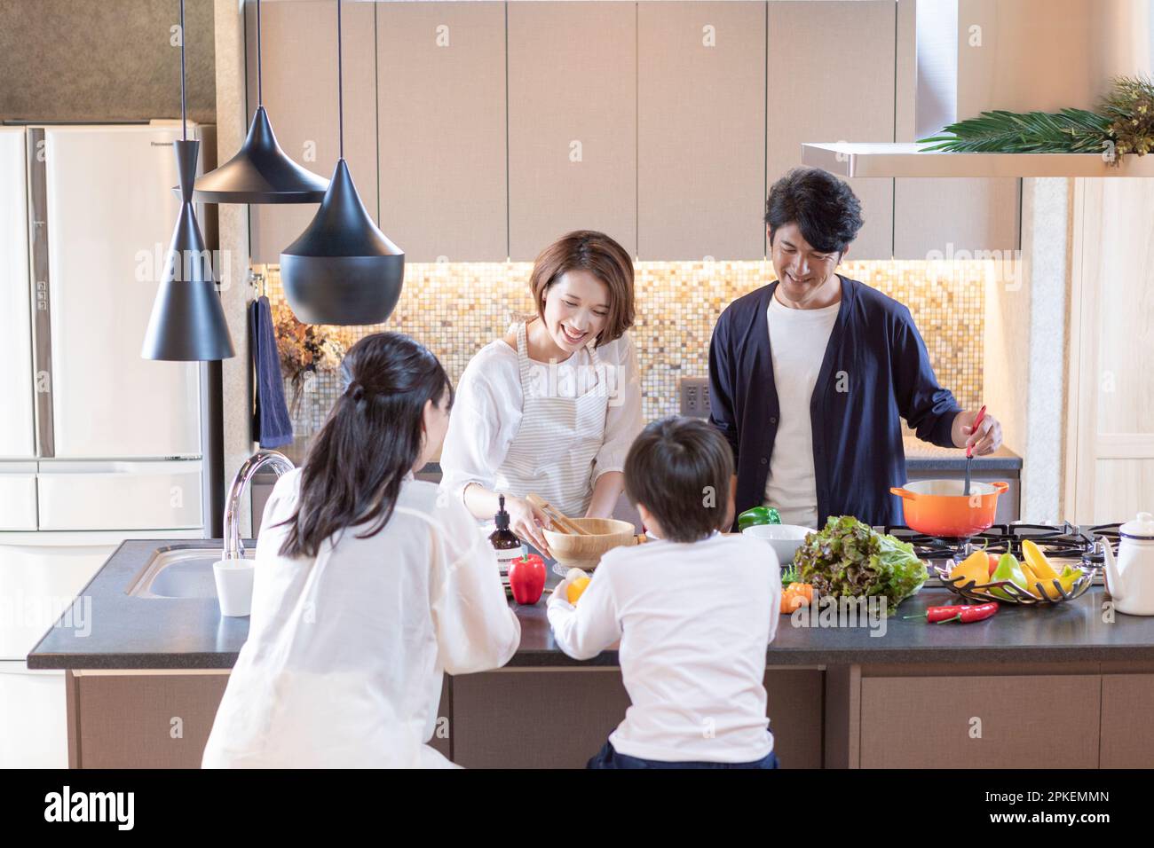 A couple standing in the kitchen with a talking brother and sister ...