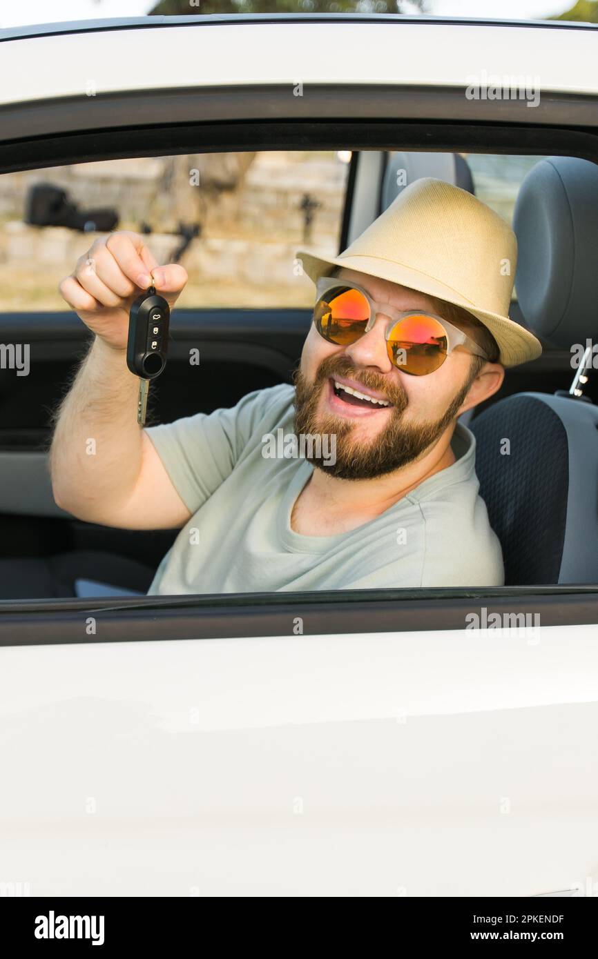 Car driver man smiling showing new car keys and car. Bearded guy ...