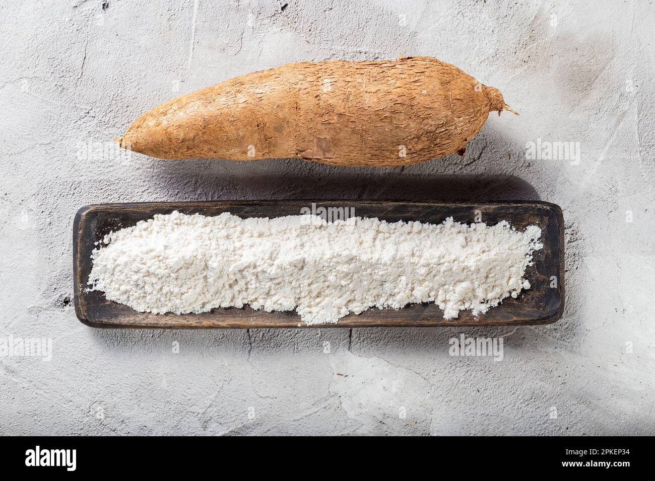 pile of cassava root and cassava flour on a gray and white textured ...