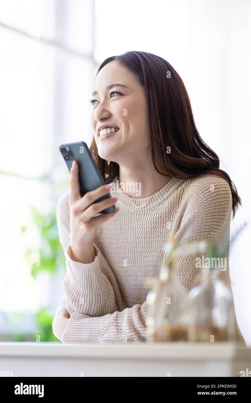 Woman looking out window with phone Stock Photo - Alamy