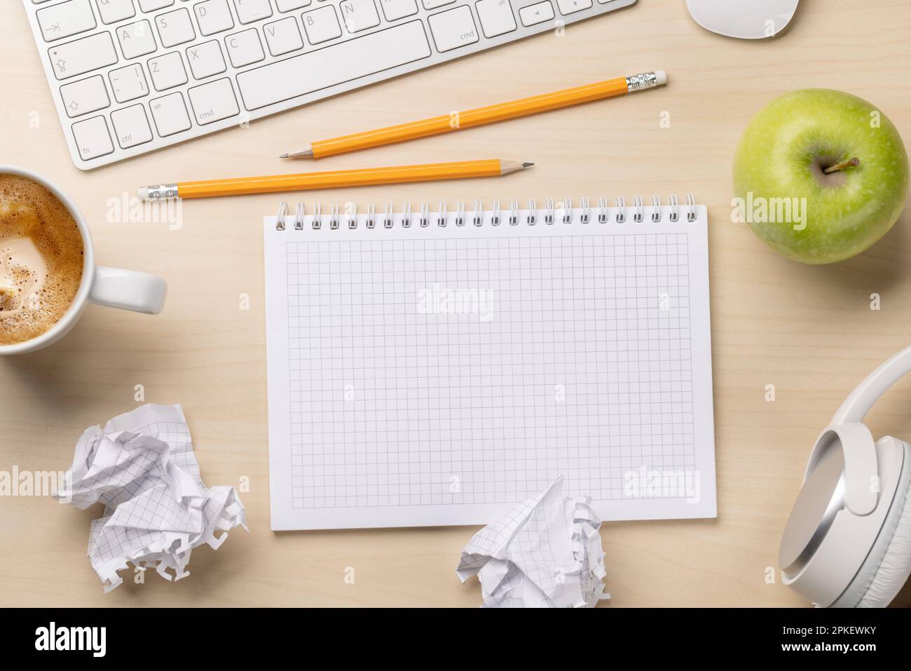 Top view of blank notepad, keyboard, headphones, apple and crumpled ...