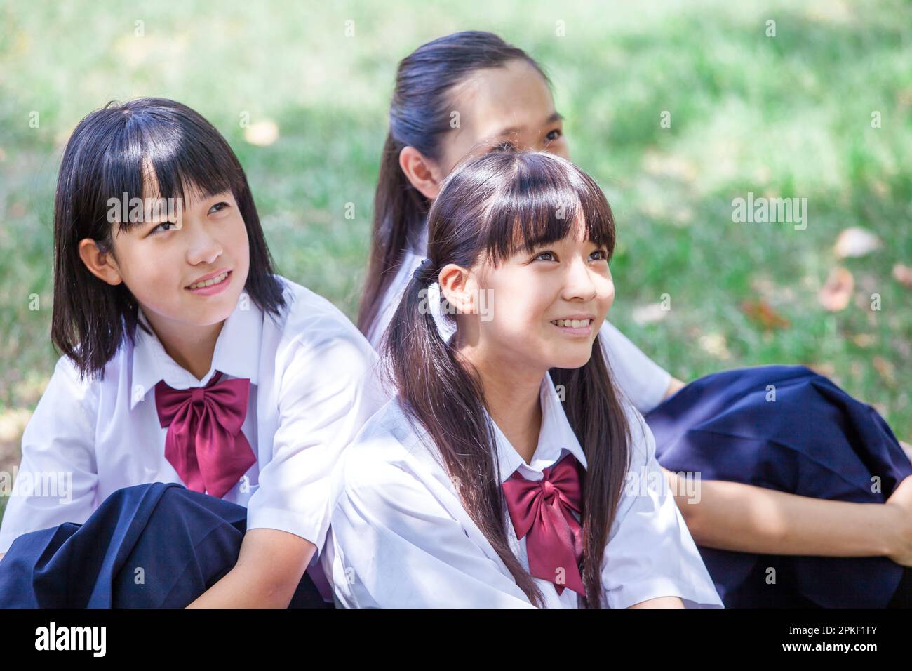 Junior high school students sitting back-to-back on a field Stock Photo ...