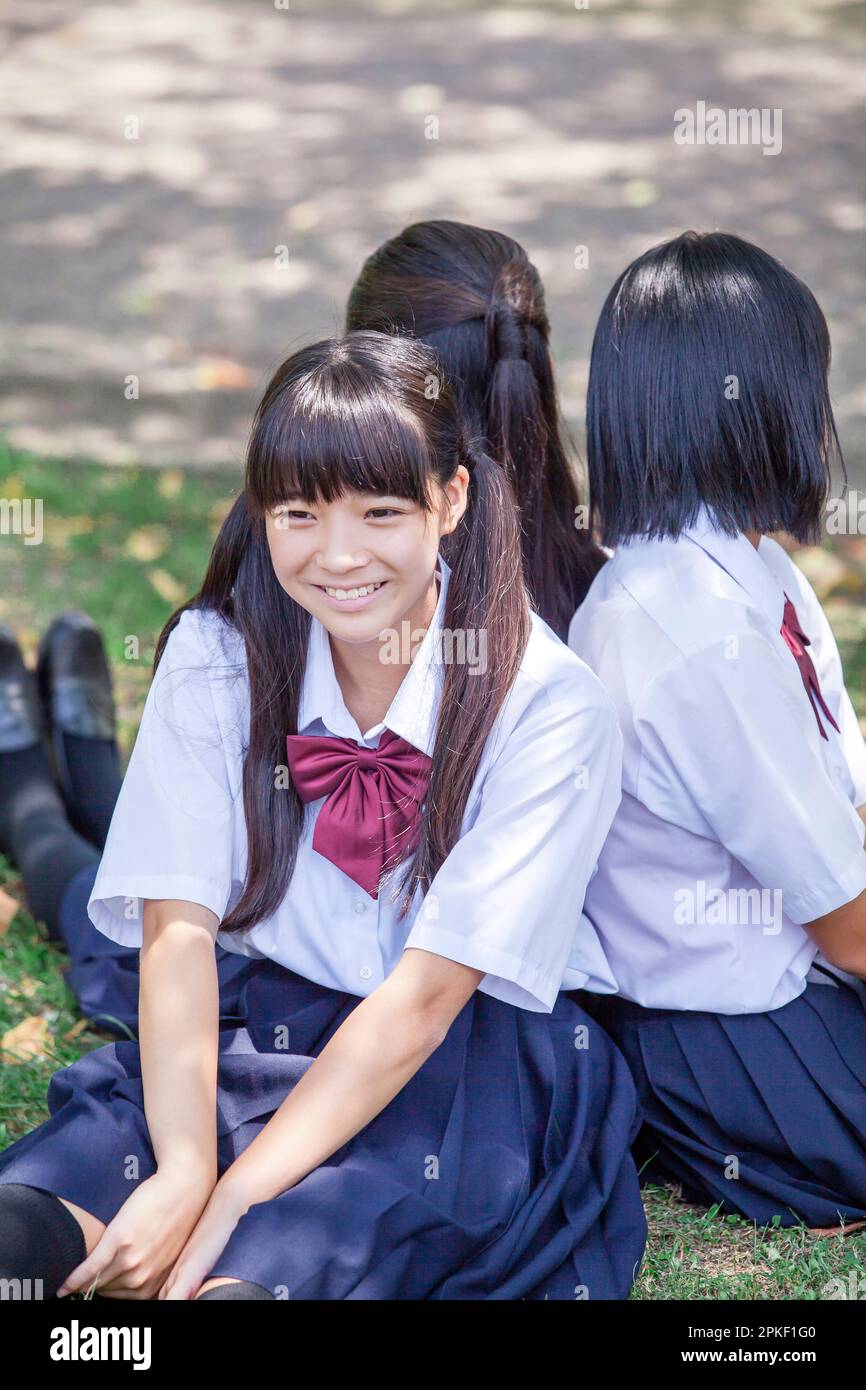 Junior high school students sitting back-to-back on a field Stock Photo ...