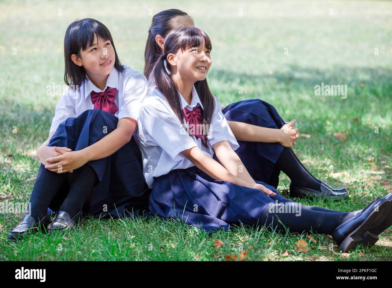 Junior high school students sitting back-to-back on a field Stock Photo ...