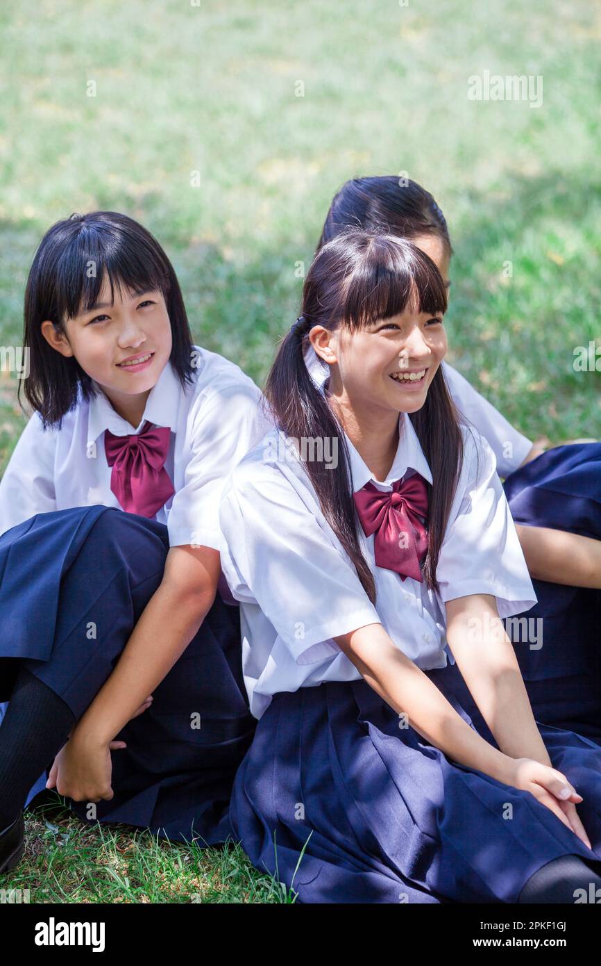 Junior high school students sitting back to back in a field Stock Photo ...