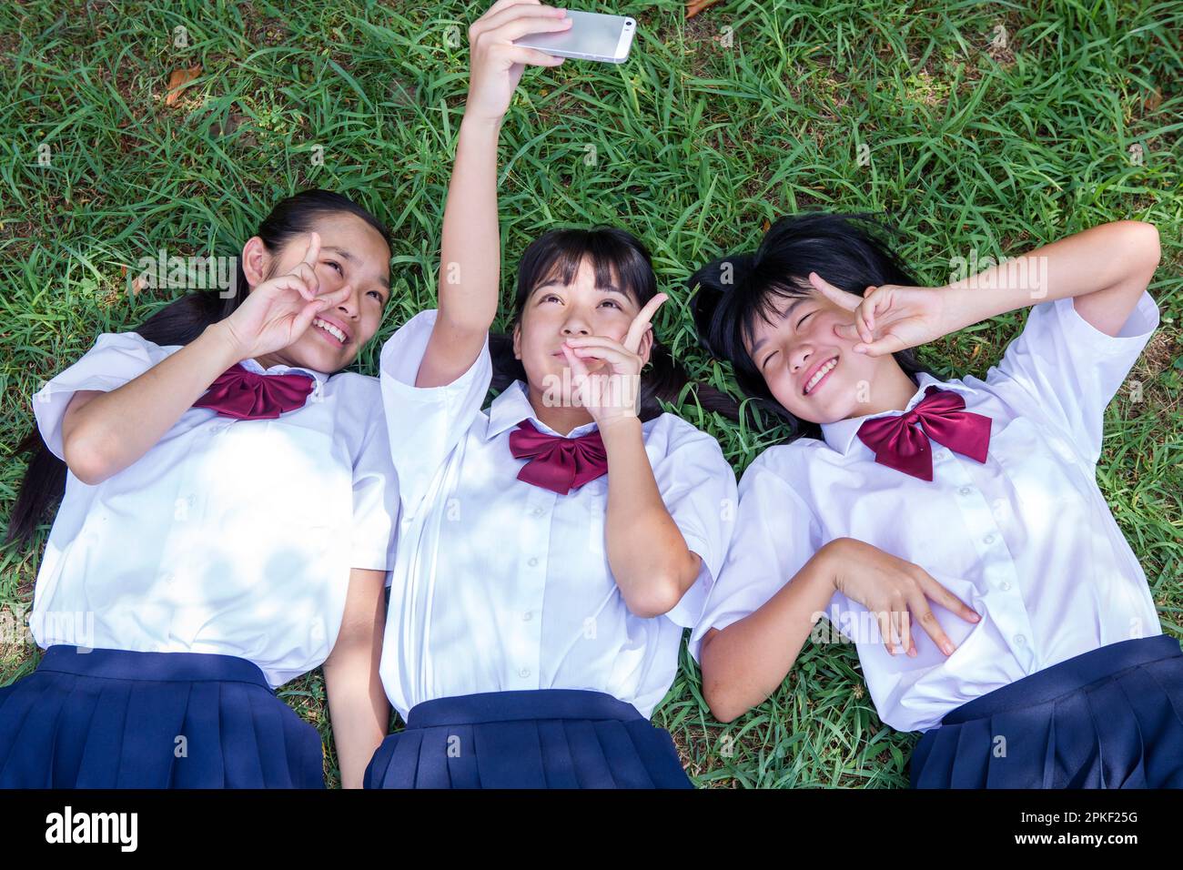 Junior high school students taking a picture lying on the grass Stock ...