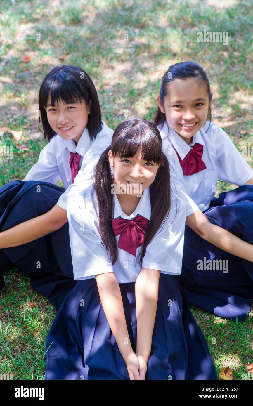 Middle school students sitting back-to-back on the grass Stock Photo ...