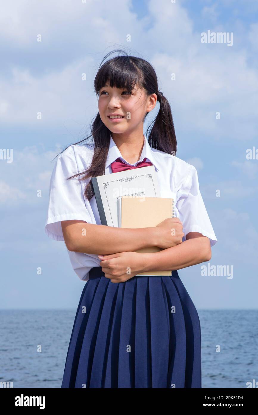 A junior high school student holding a notebook at the seaside Stock ...