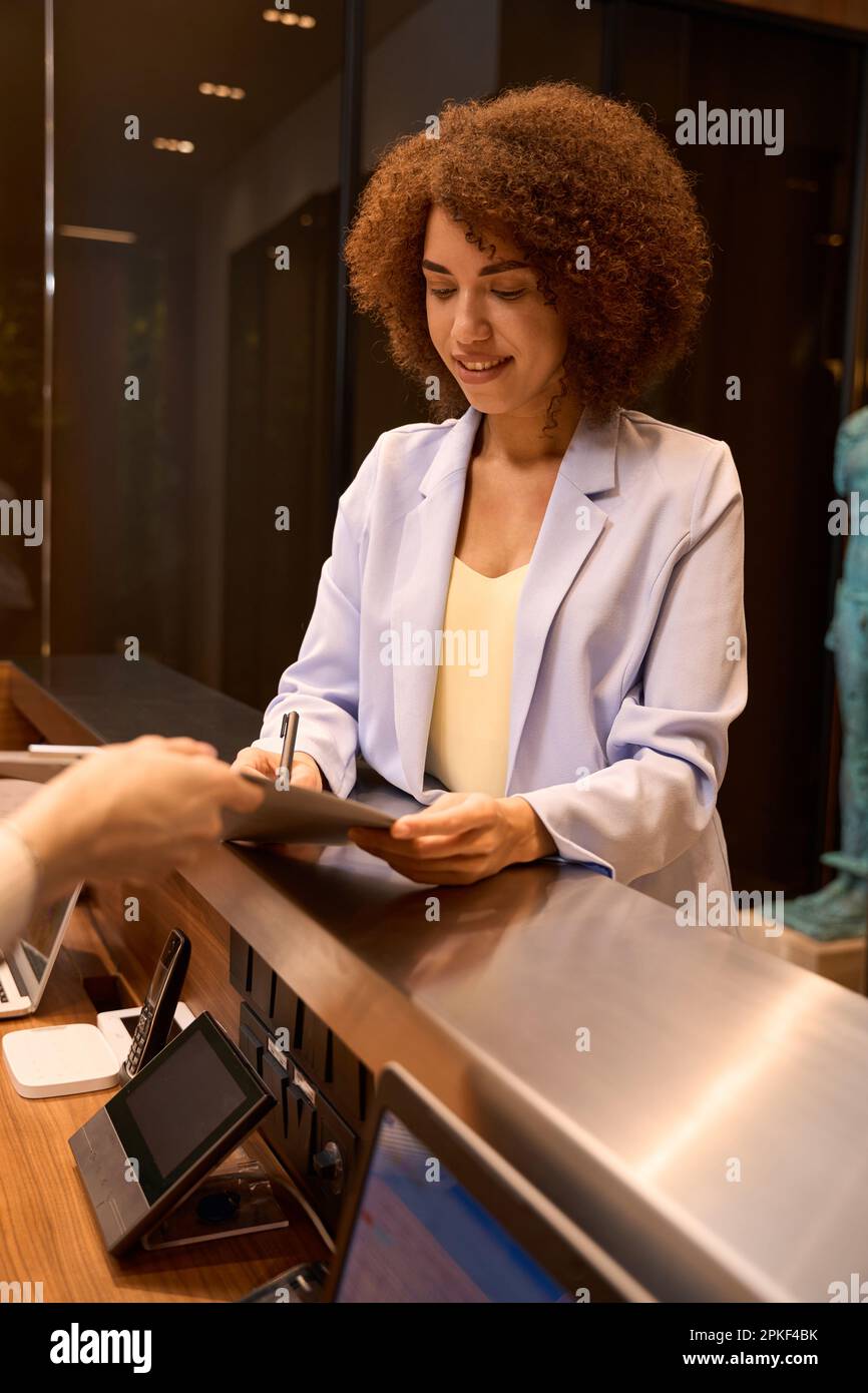 African woman filling out registration form at front desk Stock Photo ...