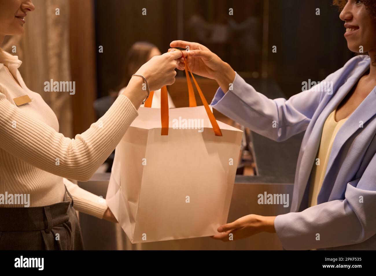 Female worker giving to customer package in lobby Stock Photo - Alamy