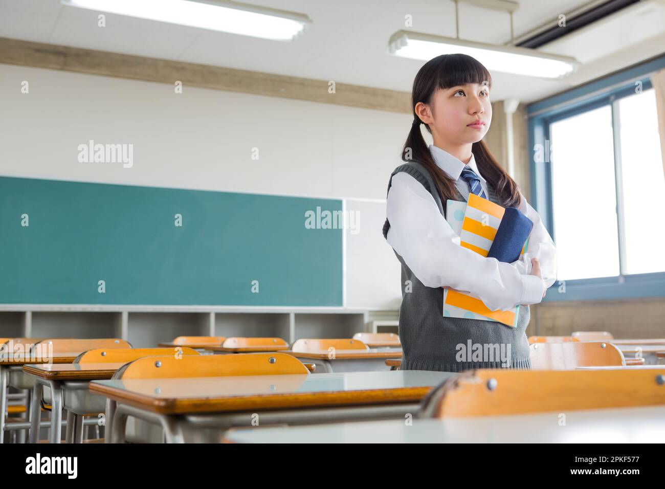 Junior high school girl holding a notebook in a classroom Stock Photo ...