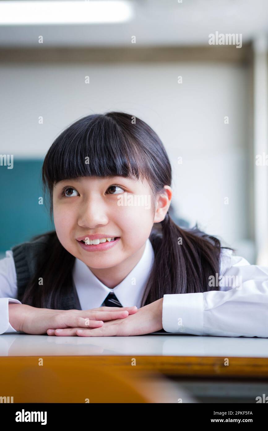 Junior high school girl leaning on a desk Stock Photo - Alamy