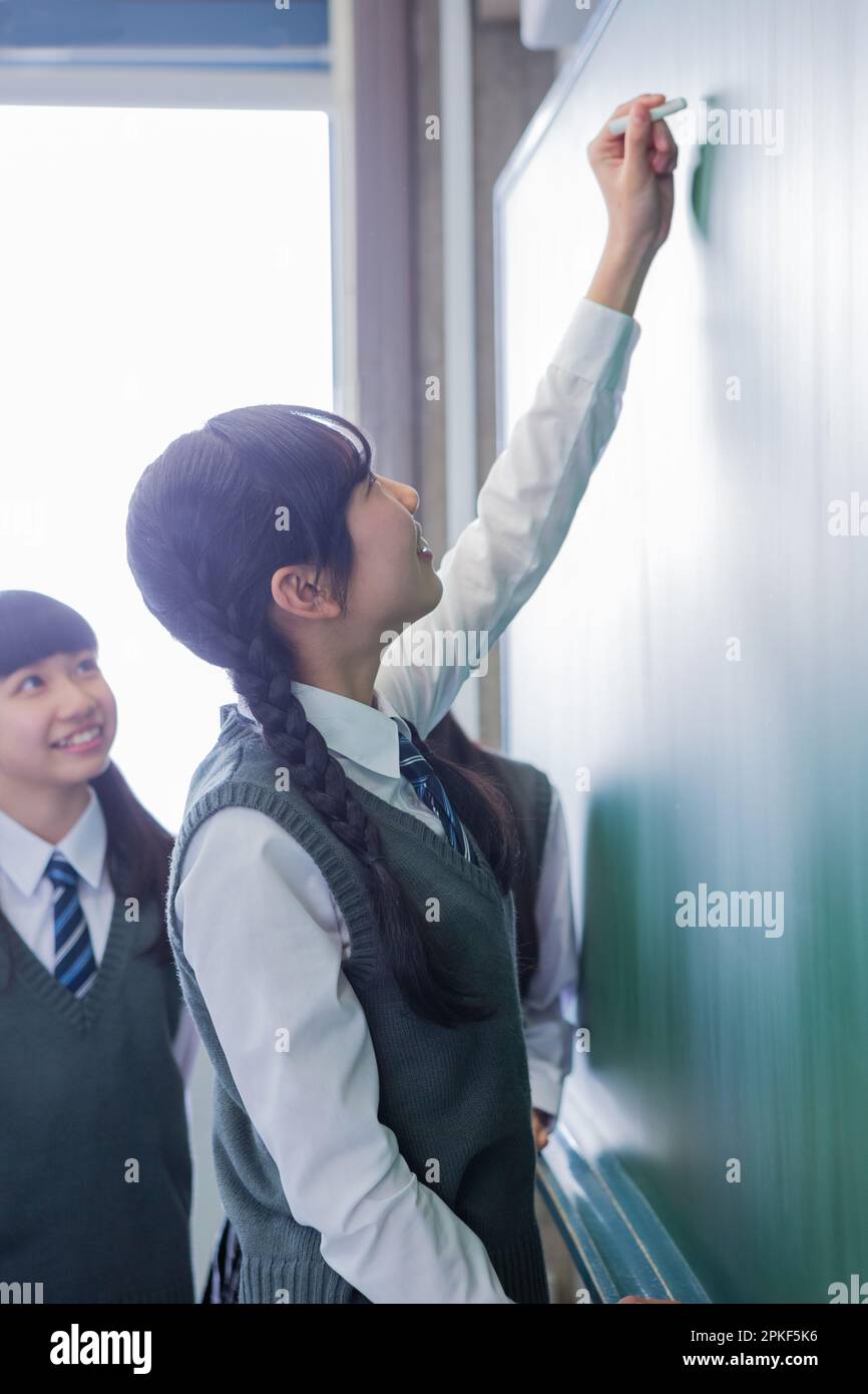 Junior high school girls writing with chalk on the blackboard Stock ...