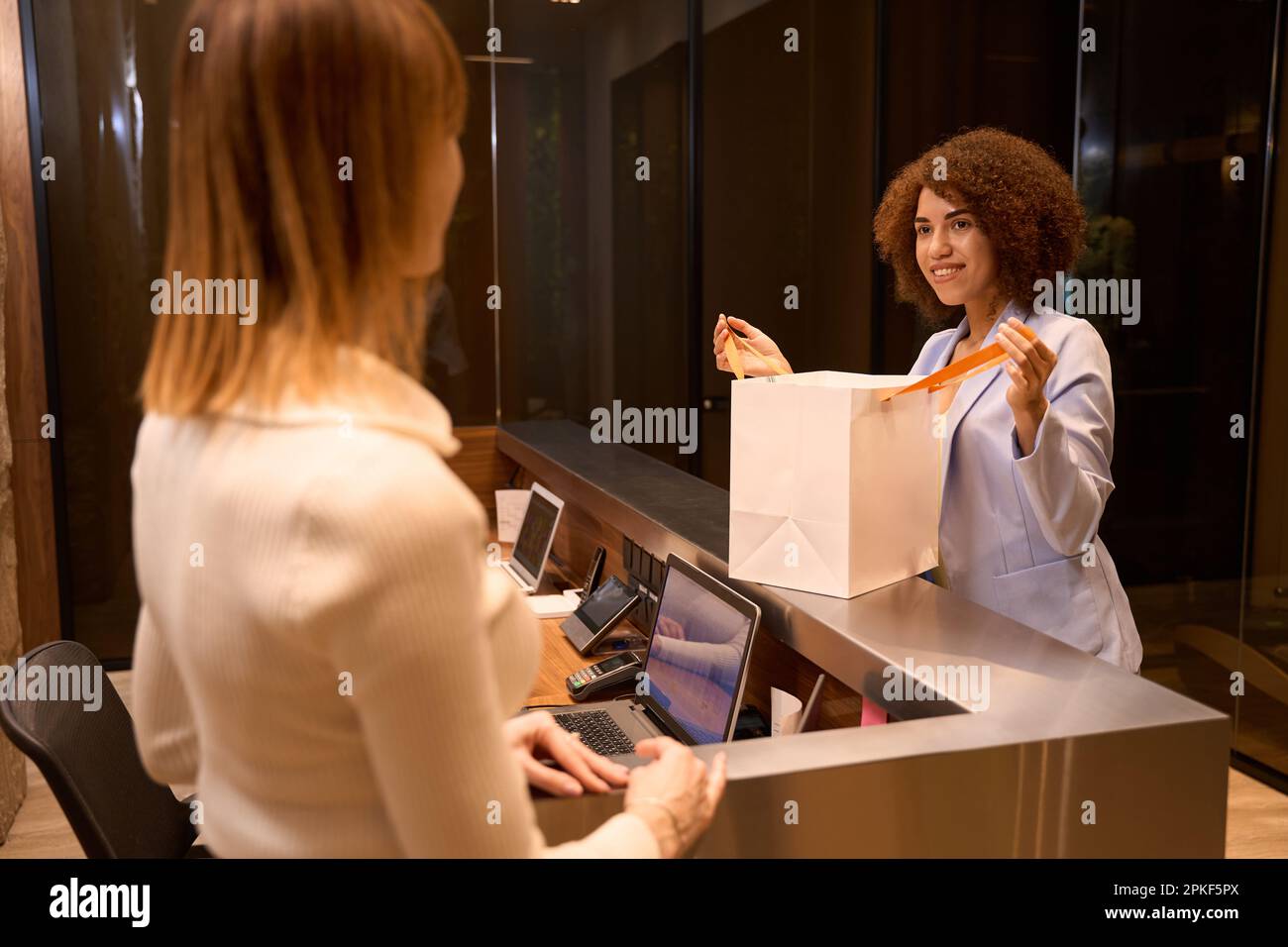 Beautiful female client unpacks packet at check in desk Stock Photo - Alamy