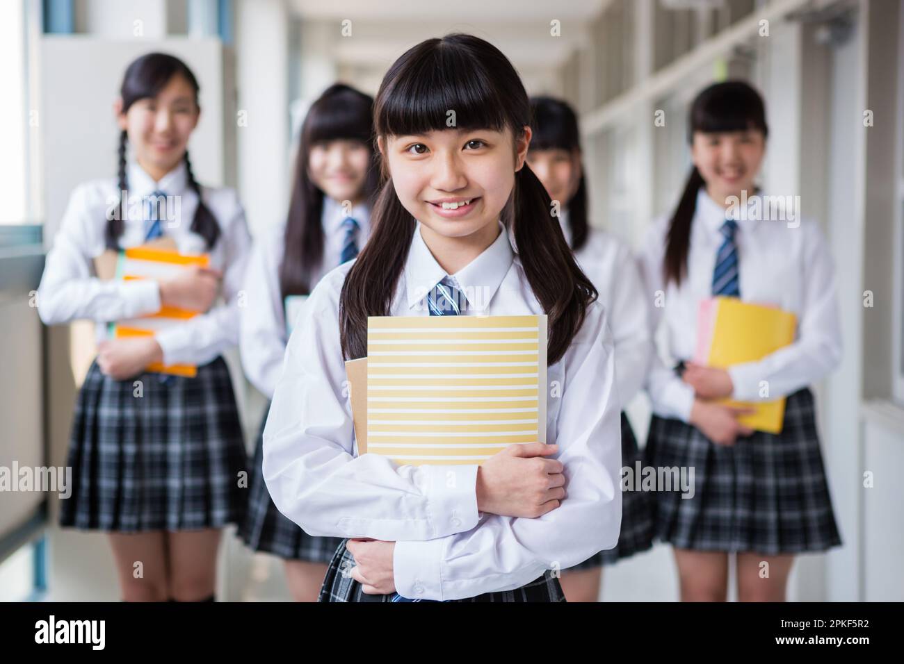 Junior high school girls holding notebooks Stock Photo - Alamy