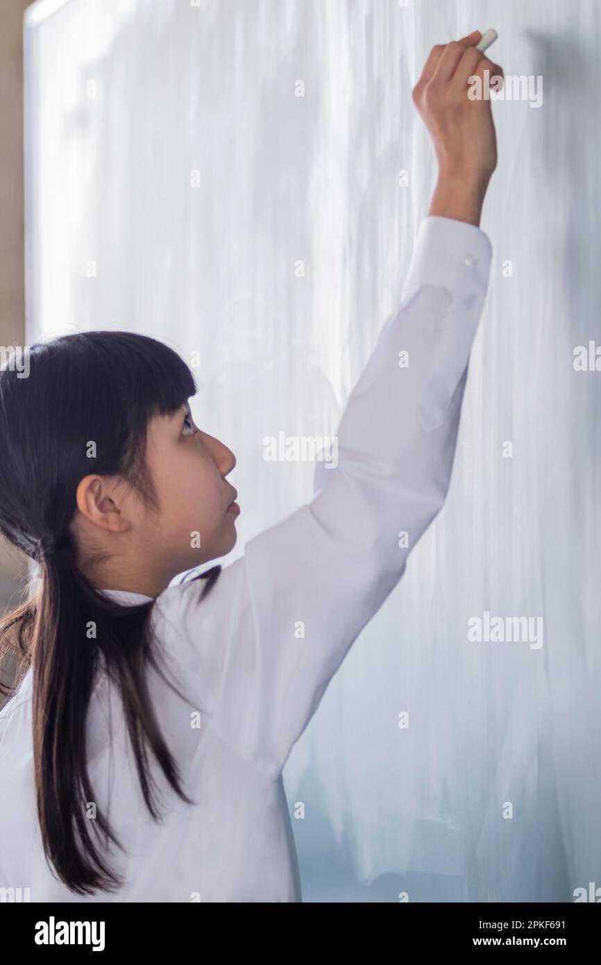 Junior high school girl writing with chalk on the blackboard Stock ...