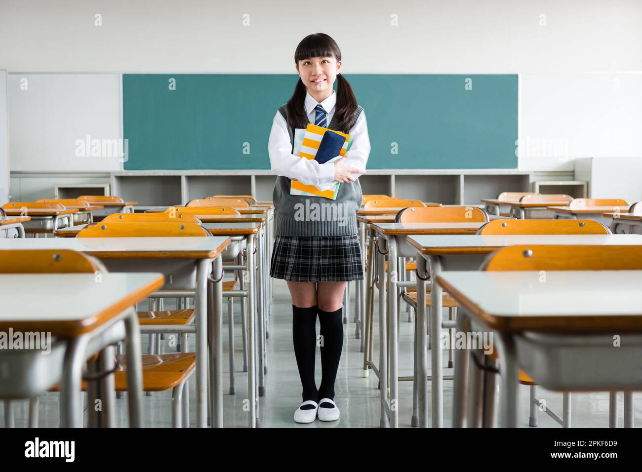 Junior high school girl holding a notebook in a classroom Stock Photo ...