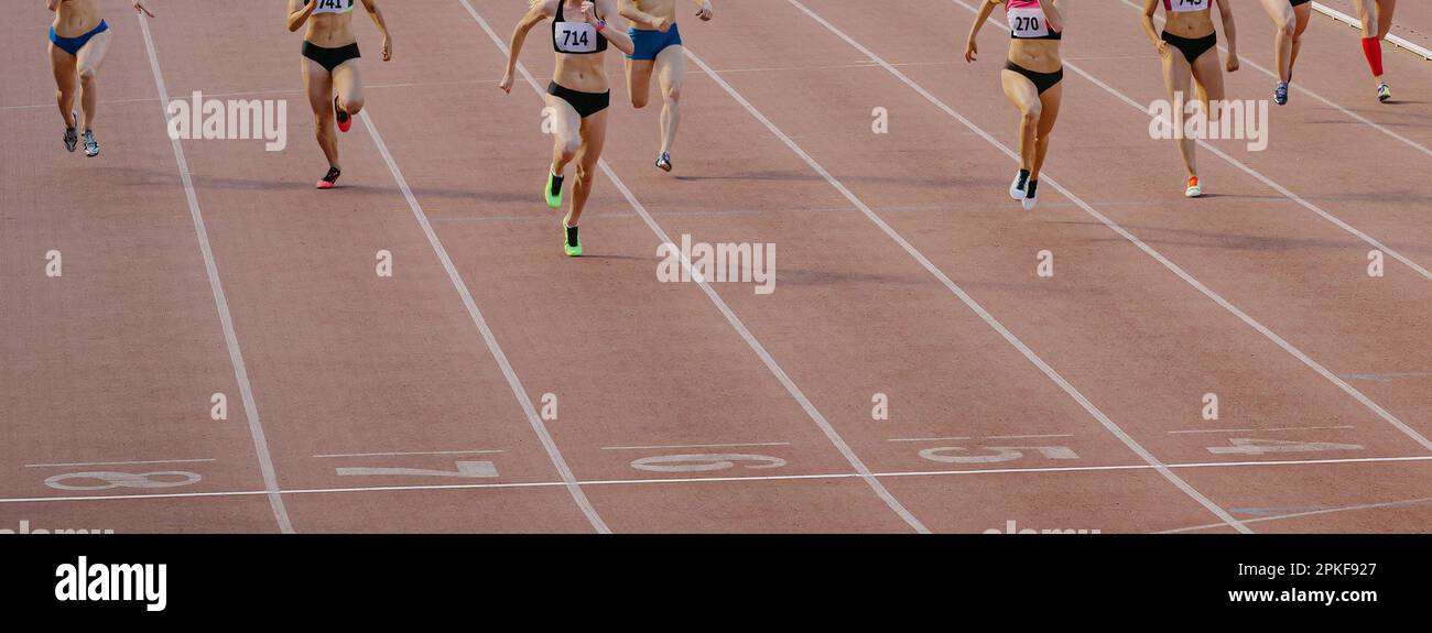 group female athletes run sprint race on stadium track, woman runner ...