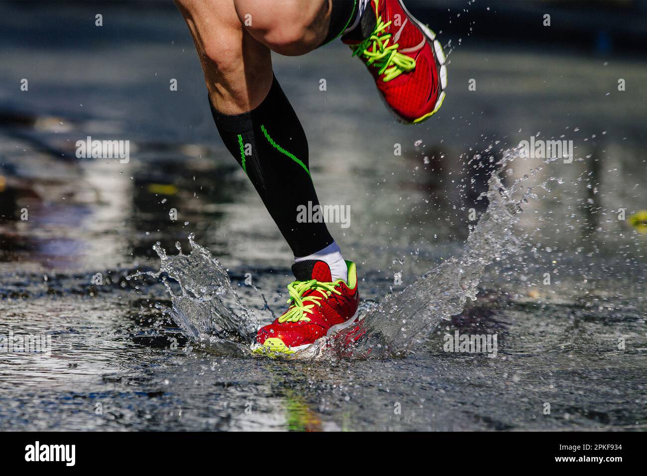legs athlete runner in compression socks running puddle on road, summer ...