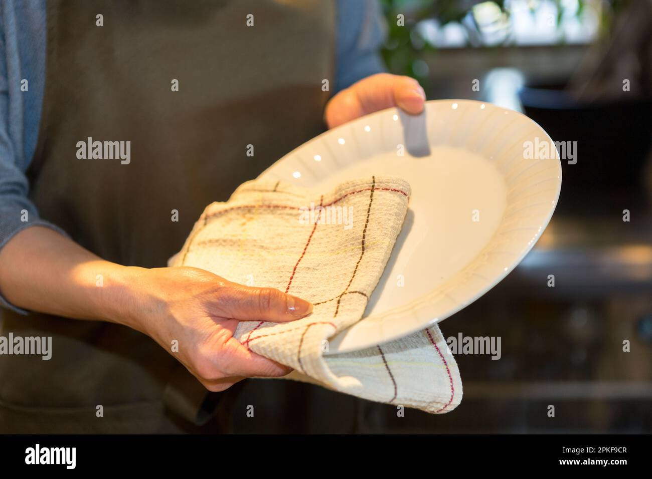 Woman wiping dishes at counter Stock Photo - Alamy