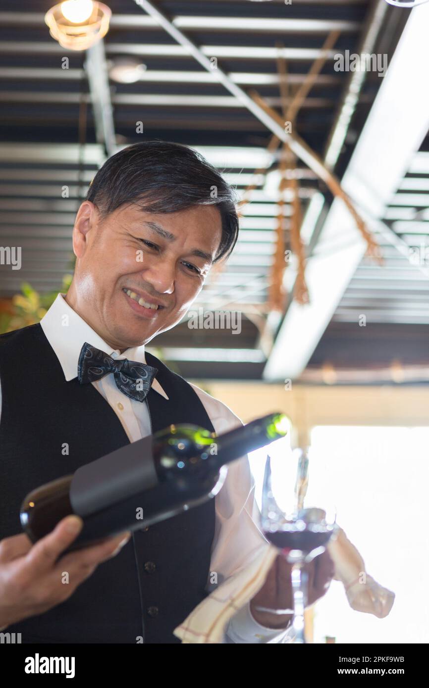 Male waiter pouring red wine Stock Photo - Alamy