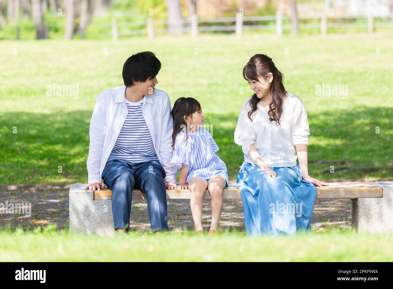 Family sitting on a bench Stock Photo - Alamy