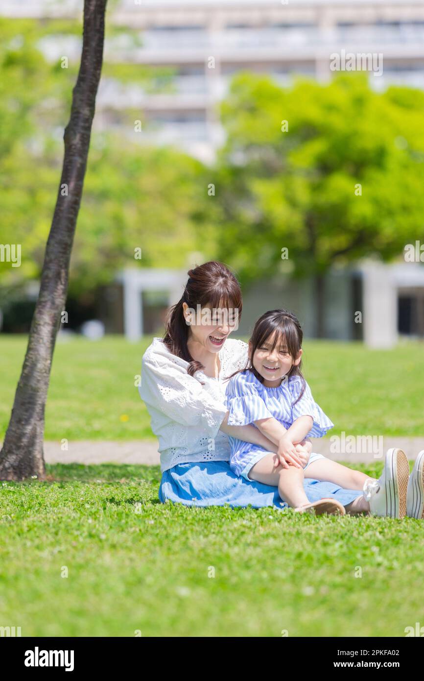 Mother sitting on the grass with her daughter on her lap Stock Photo ...
