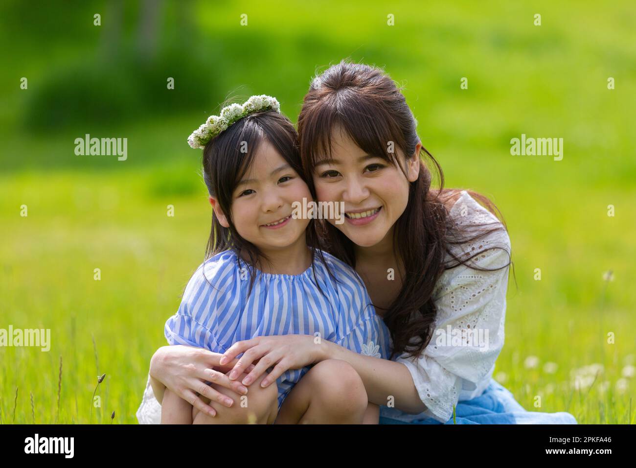 Mother and Daughter Crouching on the Grass Stock Photo - Alamy