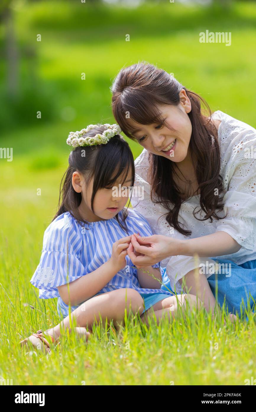 Mother and Daughter Crouching on Grass Stock Photo - Alamy