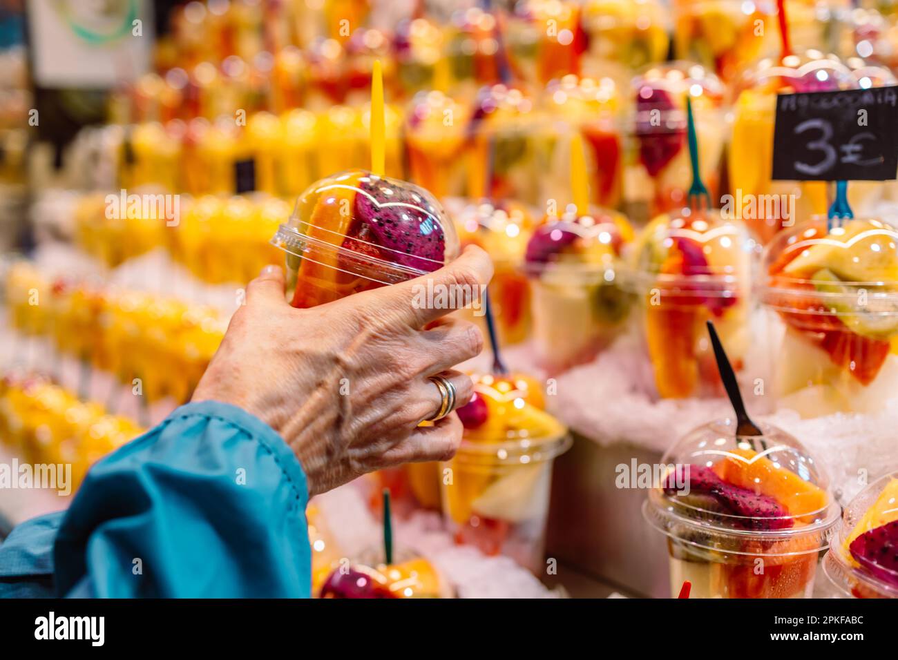 Woman choosing and takes a prepared fruit salad pots to take away in ...