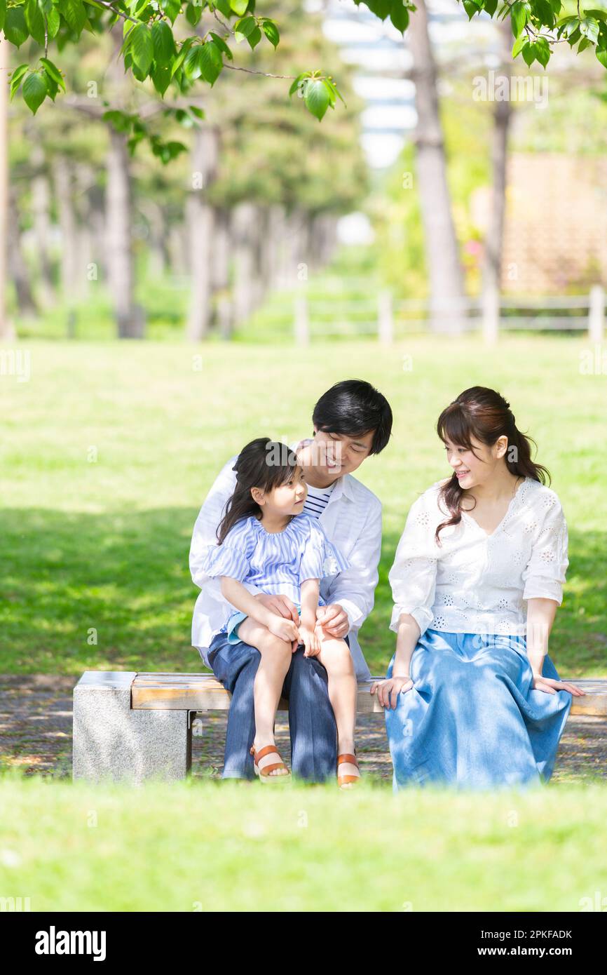 Family sitting on a bench Stock Photo - Alamy